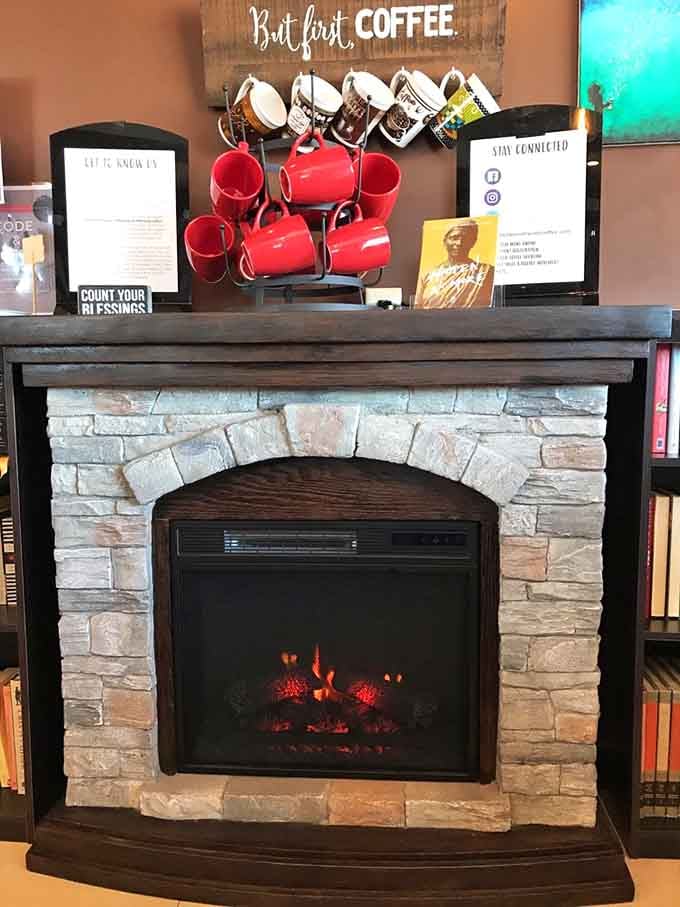 Cozy fireplace corner with coffee mugs overhead, creating ambiance that screams "cancel your afternoon plans immediately."