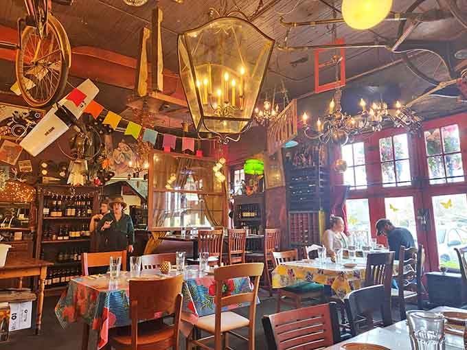 Sunlight streams through tall windows illuminating colorful tables where diners enjoy their meals beneath hanging treasures overhead.