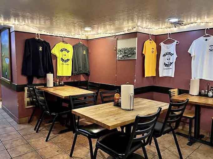 Branded tees hanging like trophies above the tables, because some fans want to wear their pizza loyalty.
