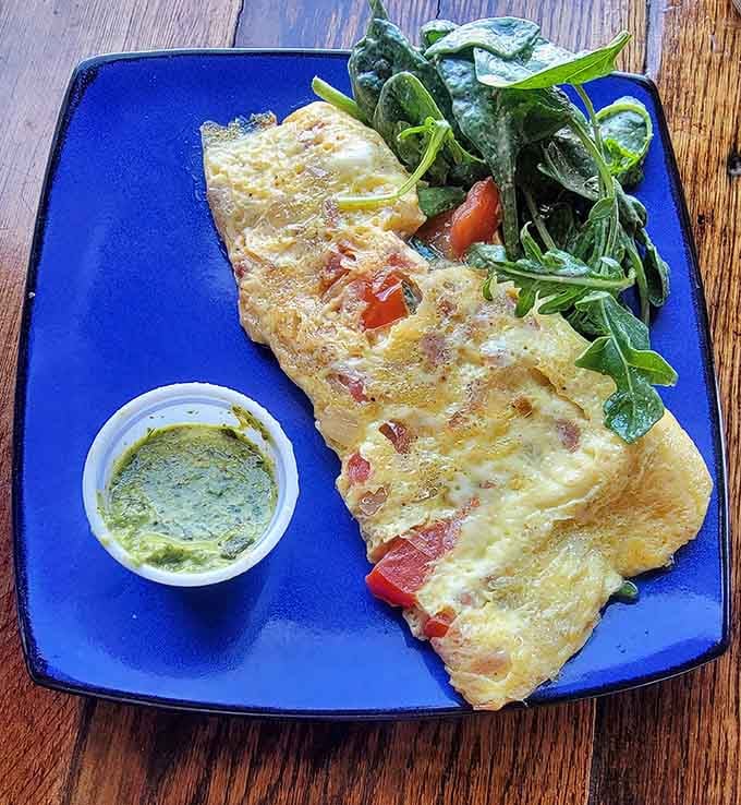 An omelet that takes breakfast seriously, loaded with ingredients and served with greens that actually look appealing for once.