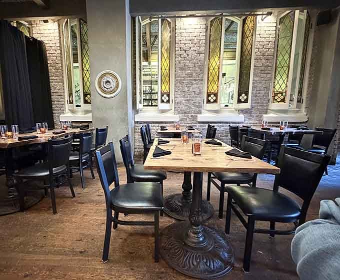 Exposed brick walls and Gothic windows frame intimate dining tables where history and contemporary design blend seamlessly together perfectly.
