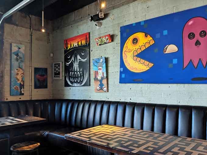 Pac-Man chomping ghosts on the wall while you relax in tufted booths, surrounded by gaming nostalgia.