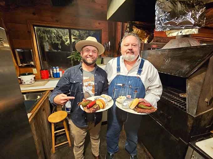 Two happy folks holding plates by the grill capture the spirit of a place where cooking is craft and eating is celebration.