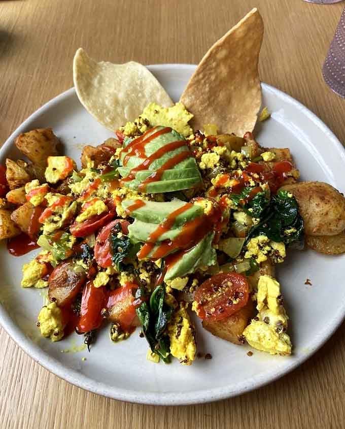 Tofu scramble loaded with veggies and drizzled with hot sauce, because plant-based eating deserves this much color.