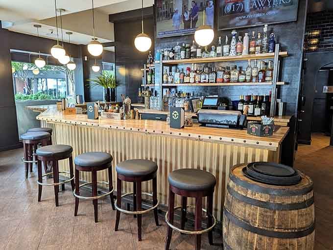 The bar features warm wood tones and a well-stocked shelf, creating the perfect spot for solo dining or pre-dinner drinks.