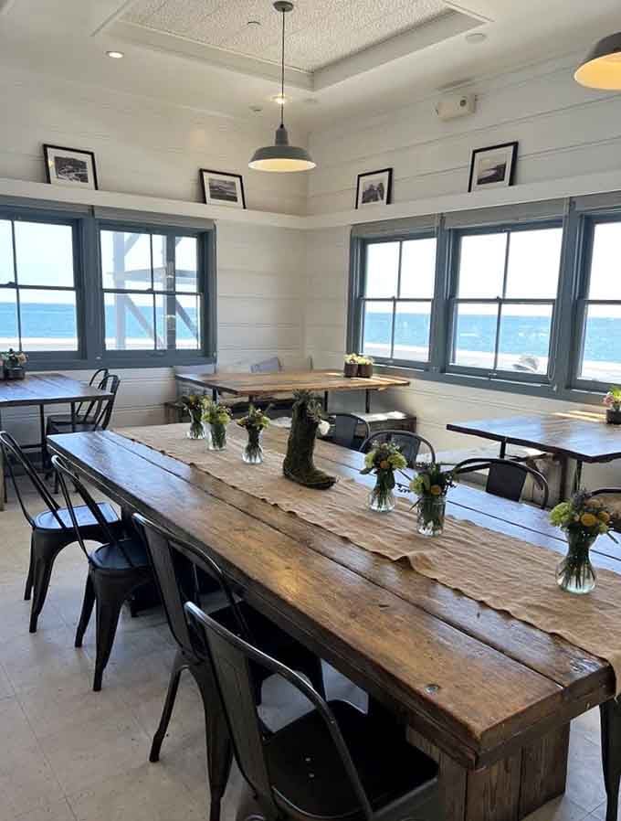 Long communal tables frame ocean panoramas through oversized windows, making every seat the best seat available.