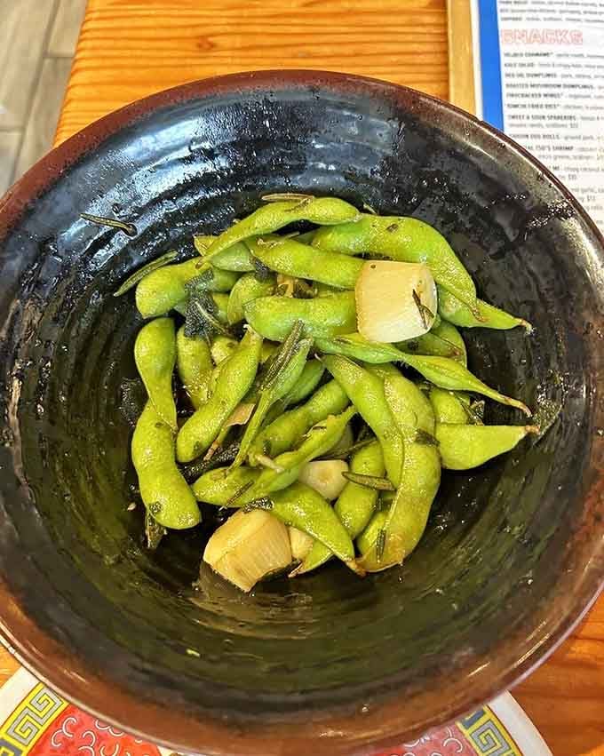 Garlicky edamame in a rustic bowl, the perfect salty snack while you contemplate your noodle choices.