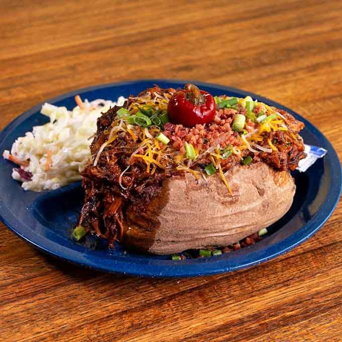A loaded baked potato topped with pulled meat and all the fixings is basically comfort food wearing a fancy hat.