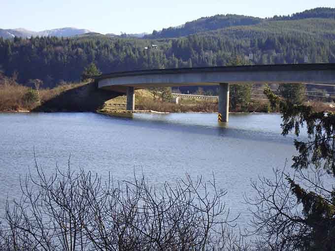 The bridge spans calm waters where kayakers glide beneath, exploring nature's highway through town.
