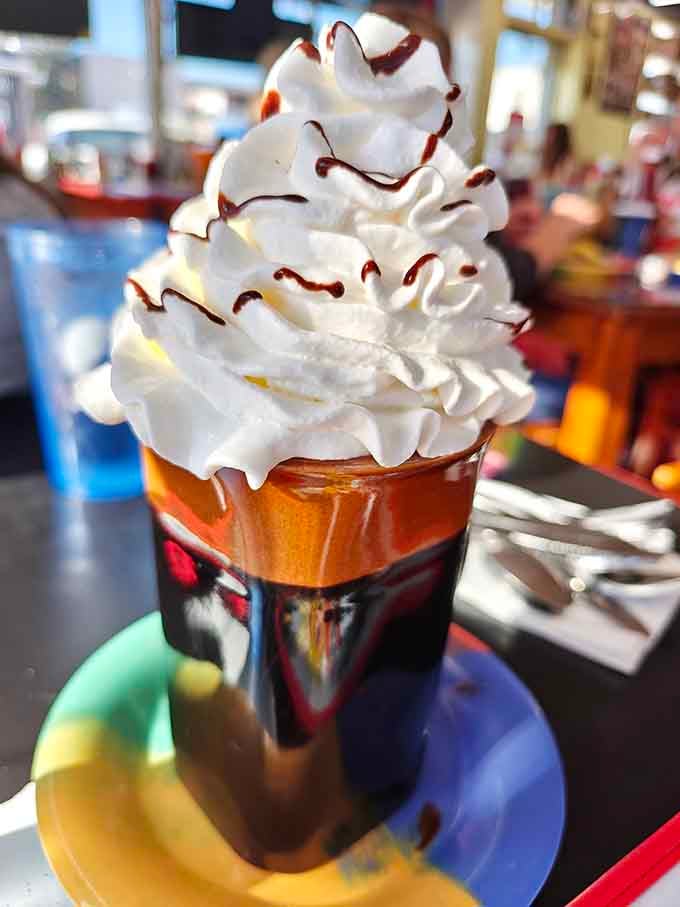 Whipped cream piled so high it's practically applying for its own weather system, with chocolate drizzle for good measure.