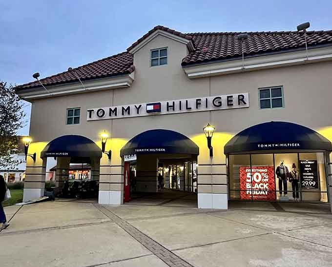Tommy Hilfiger's outlet store glowing at dusk, where preppy American style meets prices that won't make you faint.