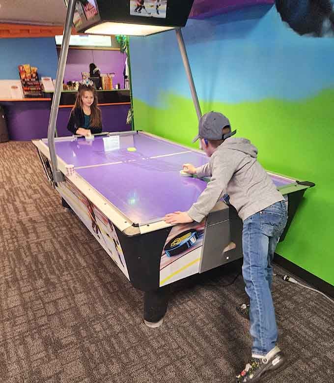 Air hockey battles rage on while the walls glow green, because sometimes competition needs the right atmospheric lighting.