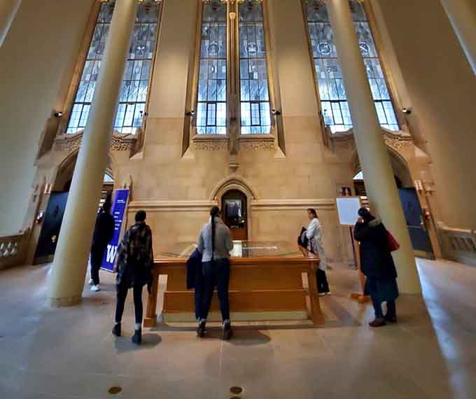 Visitors gather beneath towering windows, probably wondering if they accidentally time-traveled to medieval Europe.