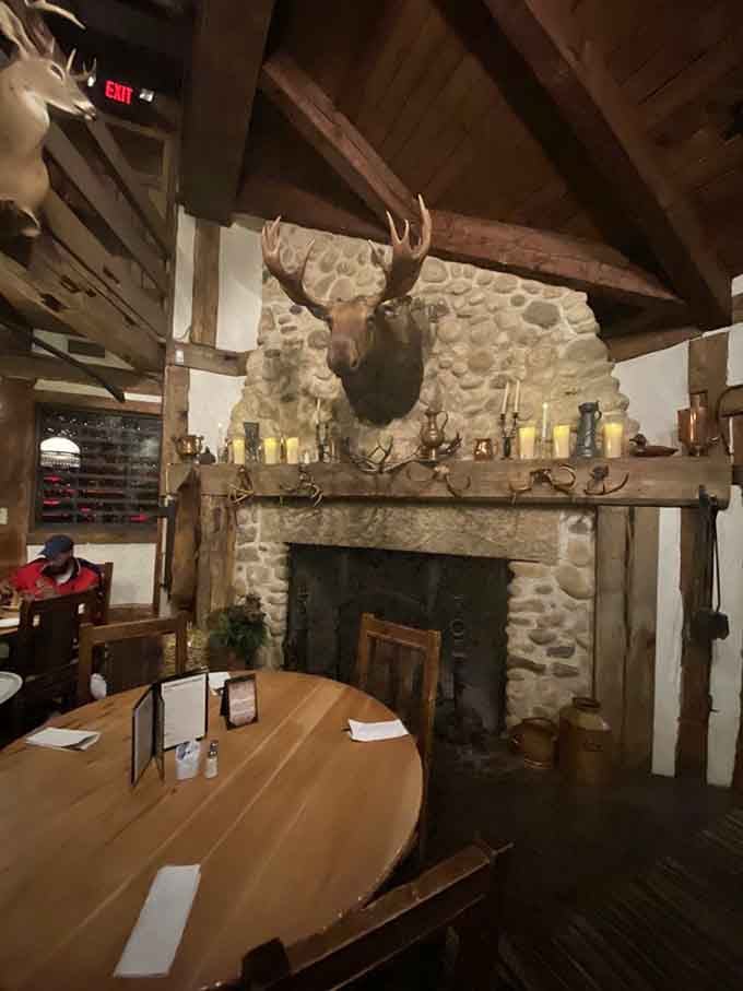 Stone fireplace topped with mounted antlers, proving this hunting lodge aesthetic isn't playing around with half measures here.