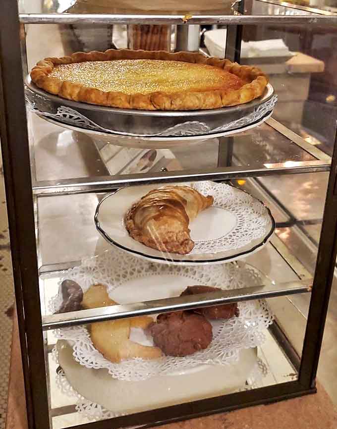 Golden custard pie and flaky pastries displayed like edible museum pieces behind spotless glass.