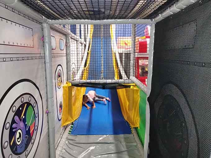 Yellow curtains frame the slide entrance like a theater stage, dramatic descent into pure childhood thrill awaits.