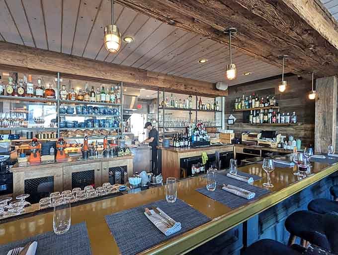 The bar invites lingering, where watching culinary artistry unfold becomes entertainment worth the front-row seat.