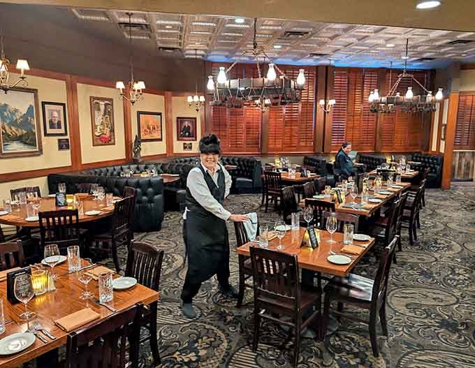 Attentive servers navigate the elegant dining room where plush booths and crisp linens set the stage for memorable meals.