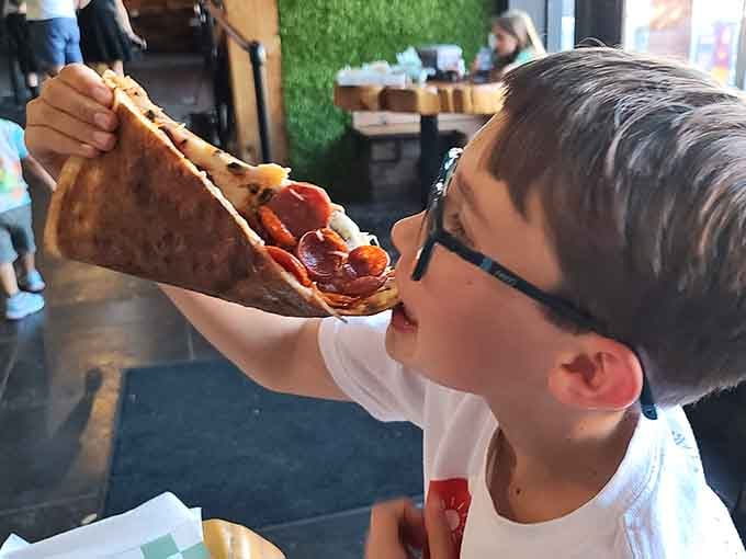 This young diner demonstrates the proper technique for tackling a slice that's almost as big as your face.