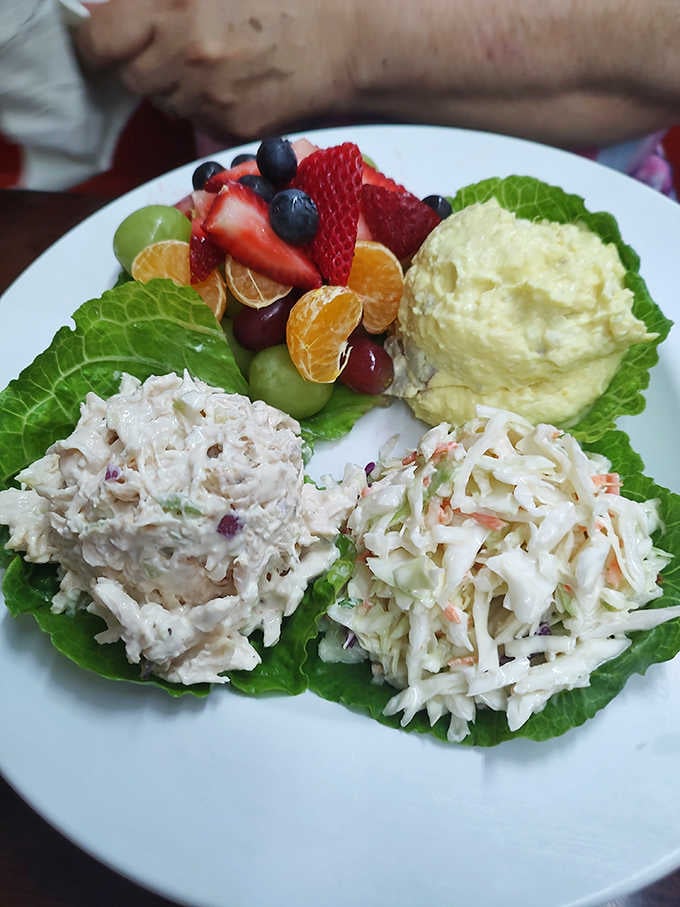 This colorful cold plate featuring chicken salad, coleslaw, potato salad, and fresh fruit is lunch done absolutely right.