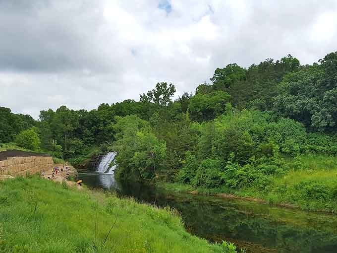 Lush greenery frames the distant falls, creating a postcard view that'll make your friends question your photography skills.