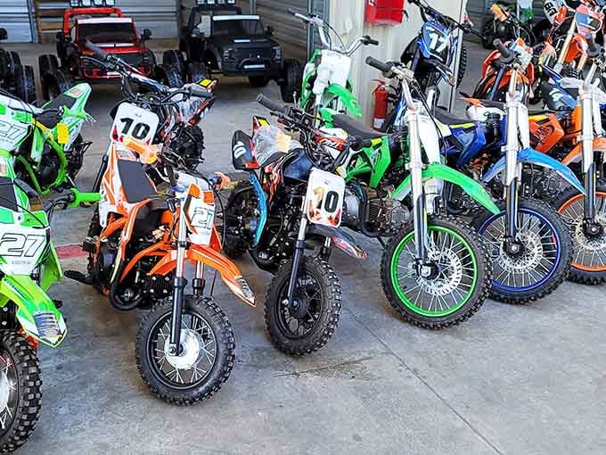 Dirt bikes and off-road motorcycles lined up like colorful soldiers ready to conquer any backyard adventure imaginable.