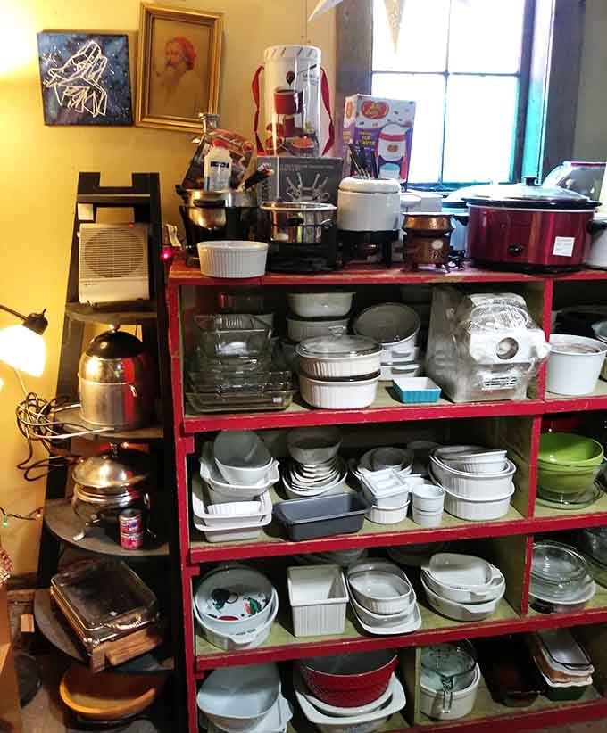 Red shelving units overflow with dishes and kitchenware that survived decades to find new homes and purposes.