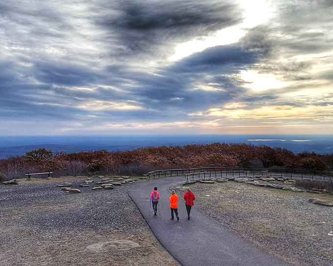 Three hikers descend under dramatic skies, their bright jackets proving safety orange never goes out of mountain fashion.