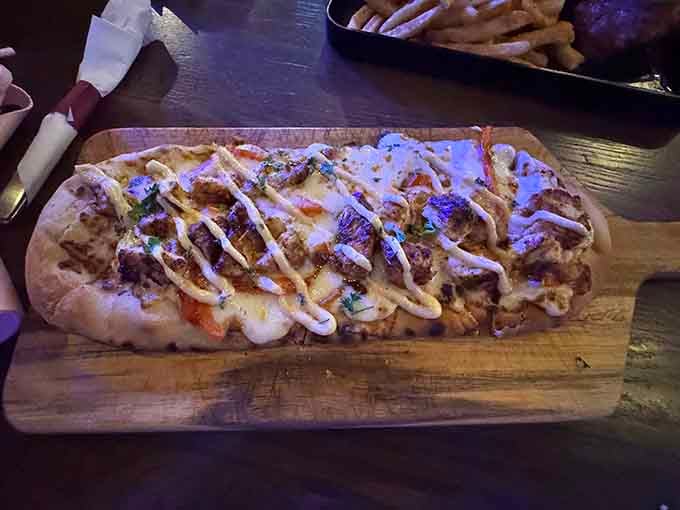 This flatbread stretches across the board like edible real estate, topped with chicken and drizzled with creamy white sauce artistry.