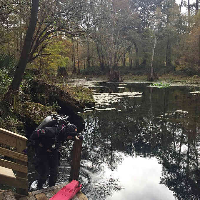 A scuba diver prepares to explore underwater passages where spring water flows clear and cold year-round.