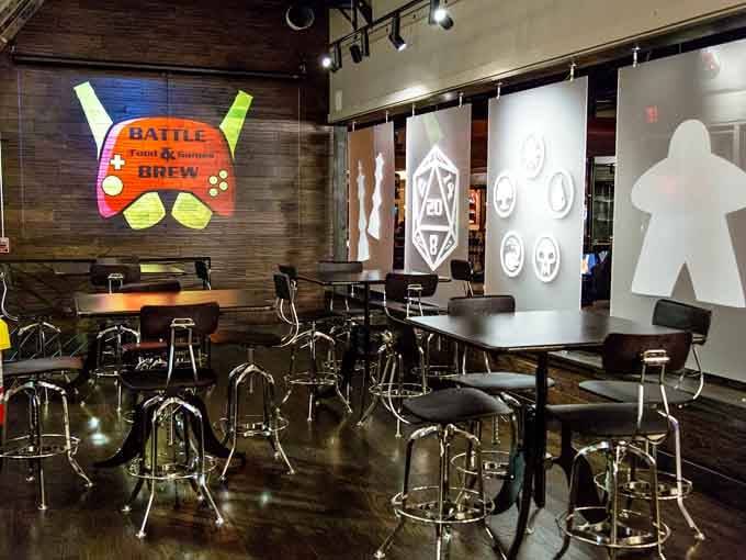 Gaming stations feature comfortable seating and giant controller artwork, blending function with playful decor throughout the space.