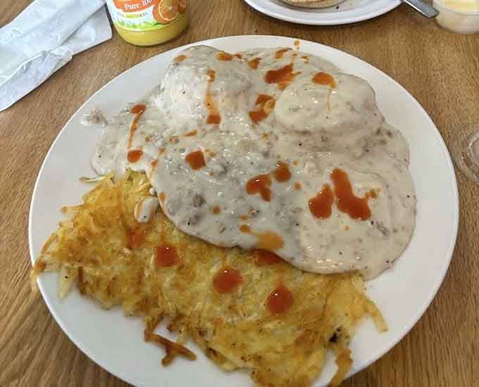 Biscuits drowning in sausage gravy with hash browns is the kind of Southern comfort that makes mornings worth waking up for.