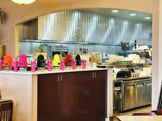 The open kitchen reveals colorful coffee carafes lined up like soldiers, ready to caffeinate the masses with precision.