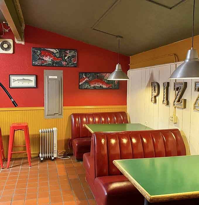 Classic red booths and pendant lights create that timeless pizzeria atmosphere where memories are made over melted mozzarella.