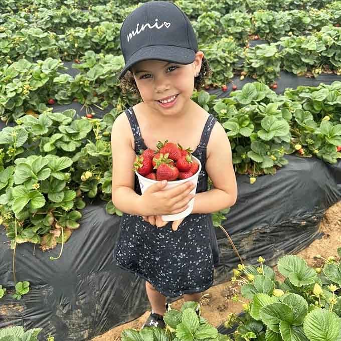 Pure pride radiates from this young picker whose bucket represents real accomplishment, not just another participation trophy moment.