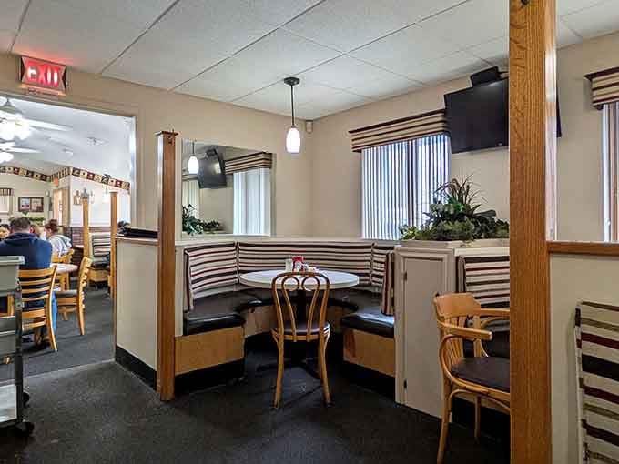 Corner booths and wooden chairs create intimate spaces where families gather and friendships deepen over shared meals.