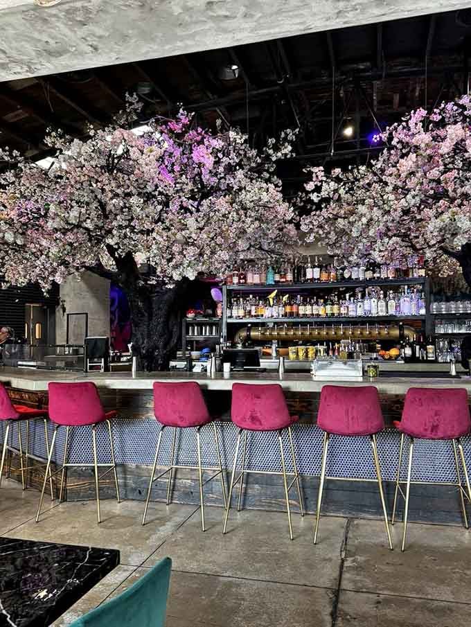 Pink bar stools line up beneath cherry blossom branches, creating the most photogenic spot to enjoy your evening cocktails.