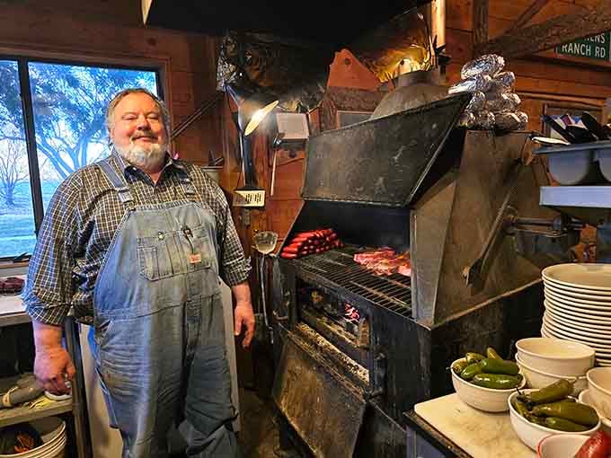 Standing proudly beside that massive grill loaded with steaks and sausages, this is clearly someone who takes meat seriously as religion.