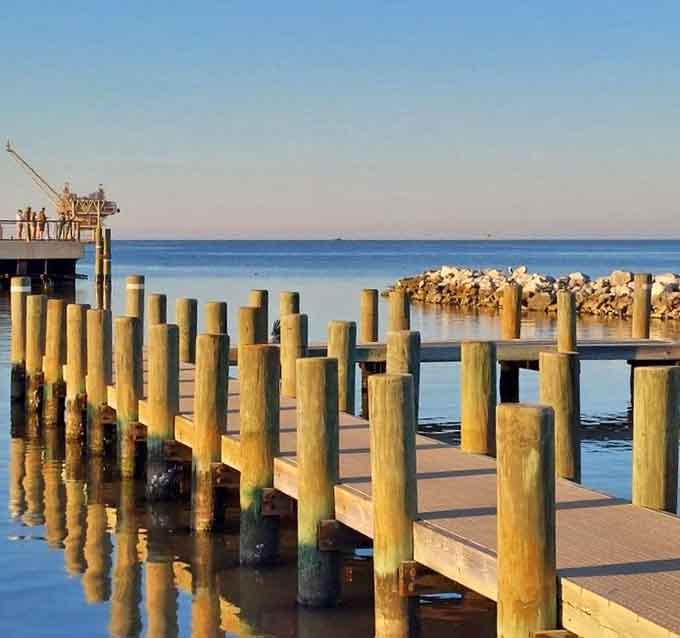 The fishing pier extends into Mobile Bay where patient anglers wait for dinner to bite, surrounded by serenity.