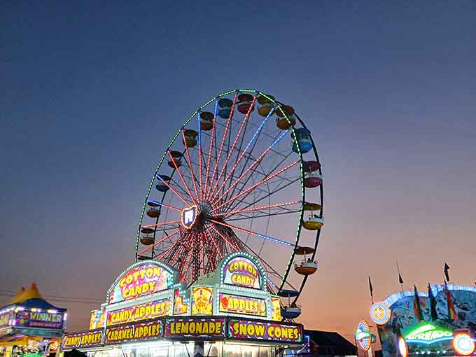 The Ferris wheel glows against twilight skies, promising cotton candy and memories worth the calories.