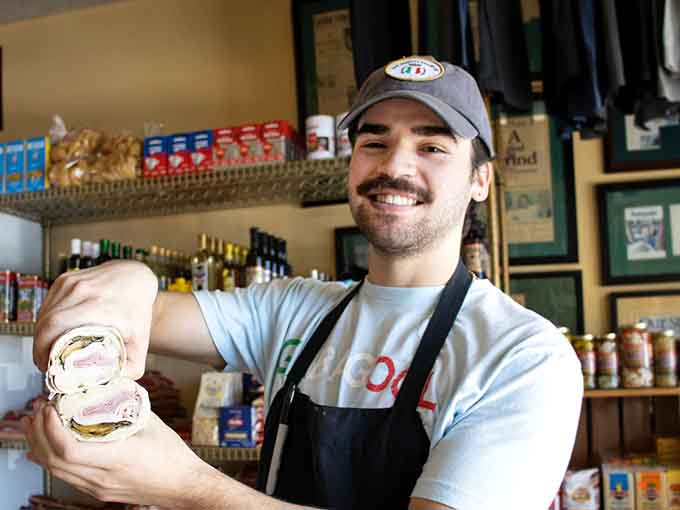 The friendly face behind the counter holding your sandwich like a proud parent presenting their overachieving child at graduation.