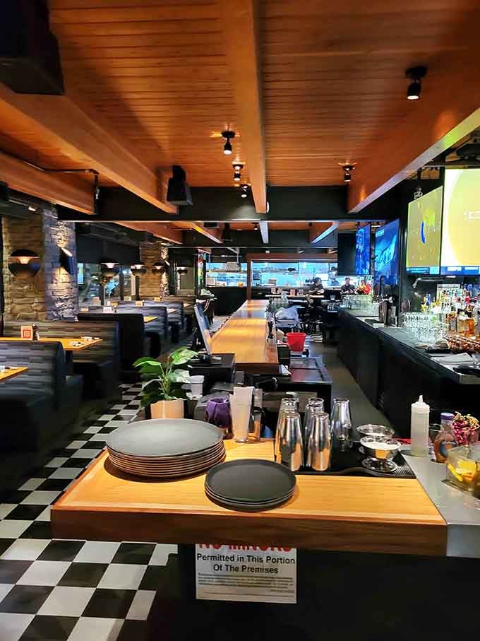 Warm wood tones and sleek bar setup create an inviting atmosphere where the checkered floor adds retro bowling charm.
