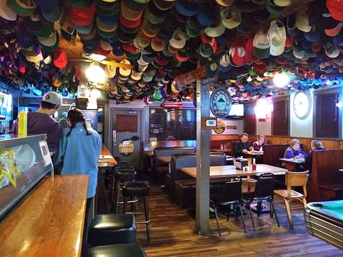 Wood paneling, baseball cups hanging from the ceiling, and comfortable chairs create the kind of tavern atmosphere that instantly feels lived-in and welcoming.