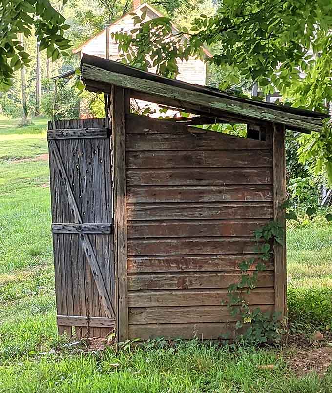 The classic wooden outhouse stands as a reminder that indoor plumbing was once considered a luxury upgrade.