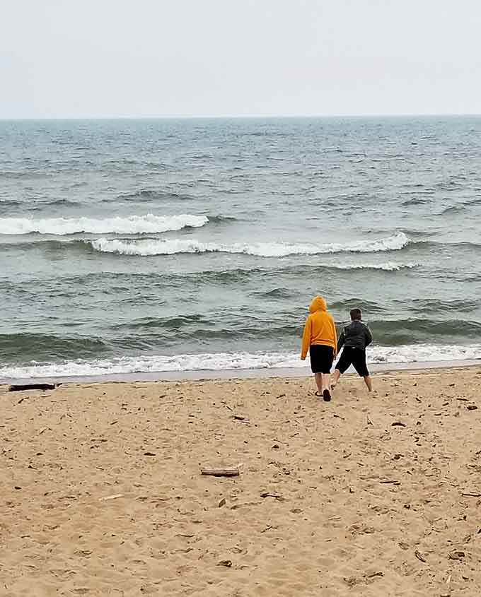Two souls braving the waves on a gray day, proving beach magic transcends perfect weather.