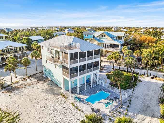 Modern beach houses rise on stilts, their colorful roofs creating a cheerful skyline against endless blue sky above.