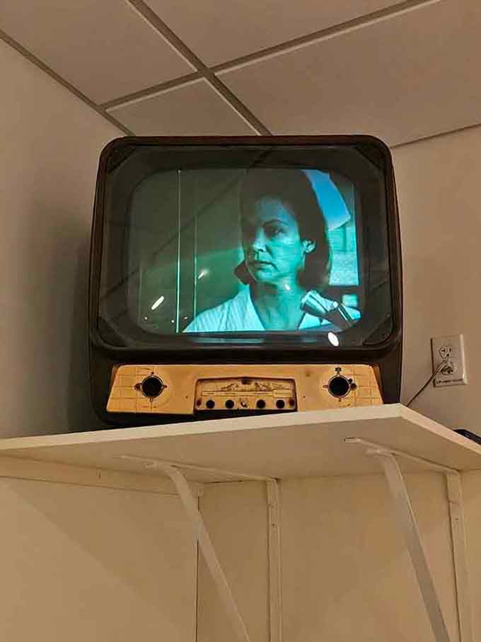 Vintage television sets played "One Flew Over the Cuckoo's Nest" clips, blurring fiction and institutional reality.