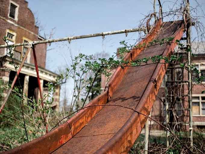 An abandoned playground slide rusts away, a heartbreaking reminder of the children who once lived here.