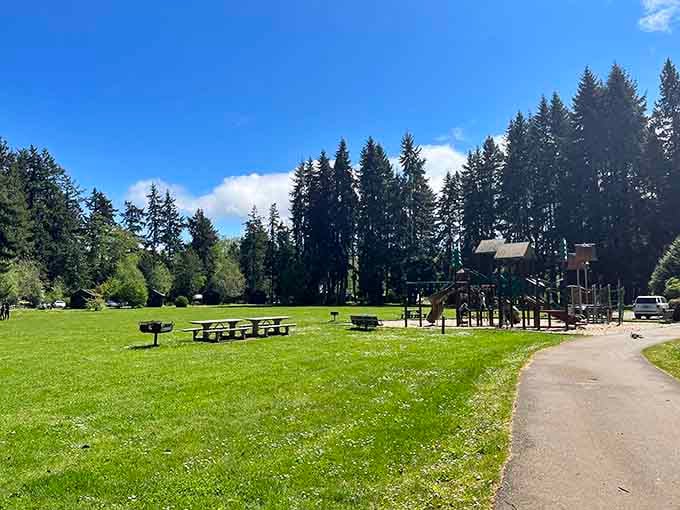 Emerald lawns stretch beneath Pacific Northwest giants, offering picnic tables and playground fun in nature's peaceful cathedral setting.