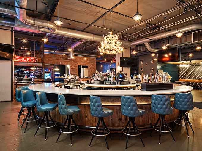 The curved bar beckons with tufted blue stools, offering craft cocktails alongside your competitive spirit tonight.